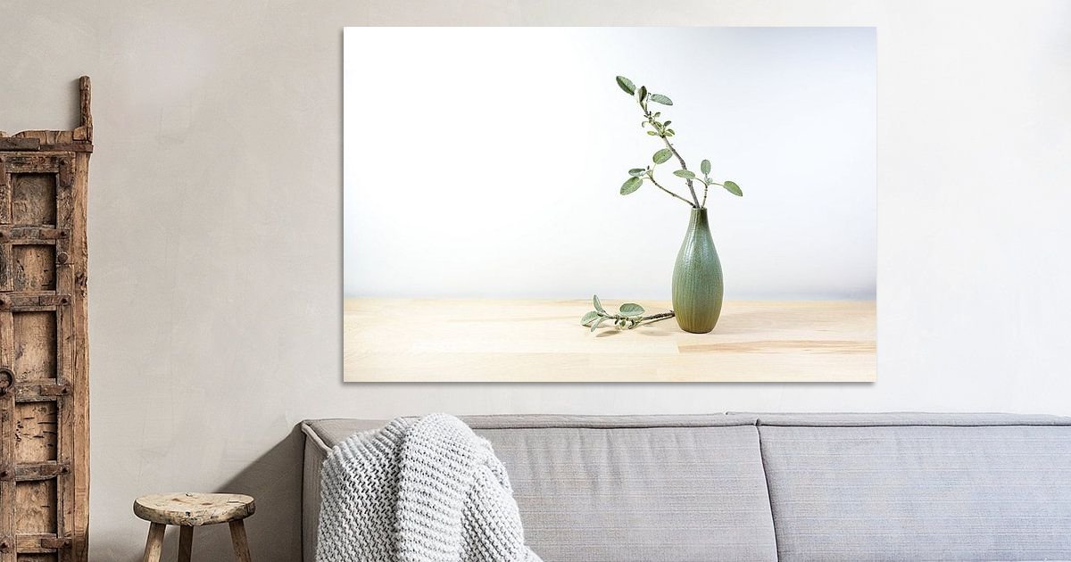 Kleine vaas met een takje salie op een lichte houten tafel of bureau ...